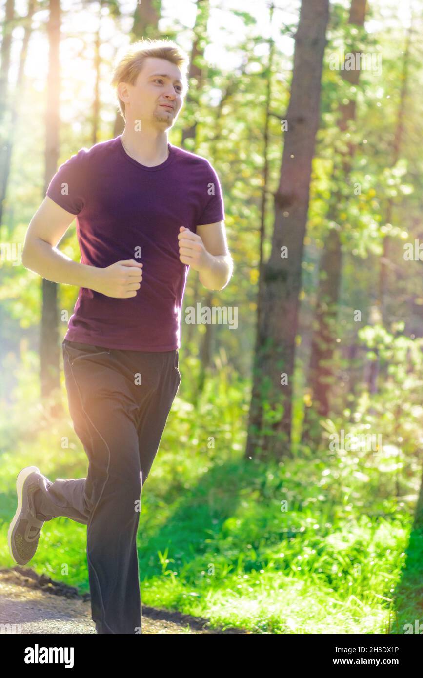 Running man jogging in city park at beautiful summer day. Sport fitness ...