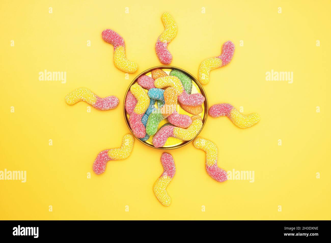 Sun shape made of multicolored sugar coated gummy worms on a yellow ...