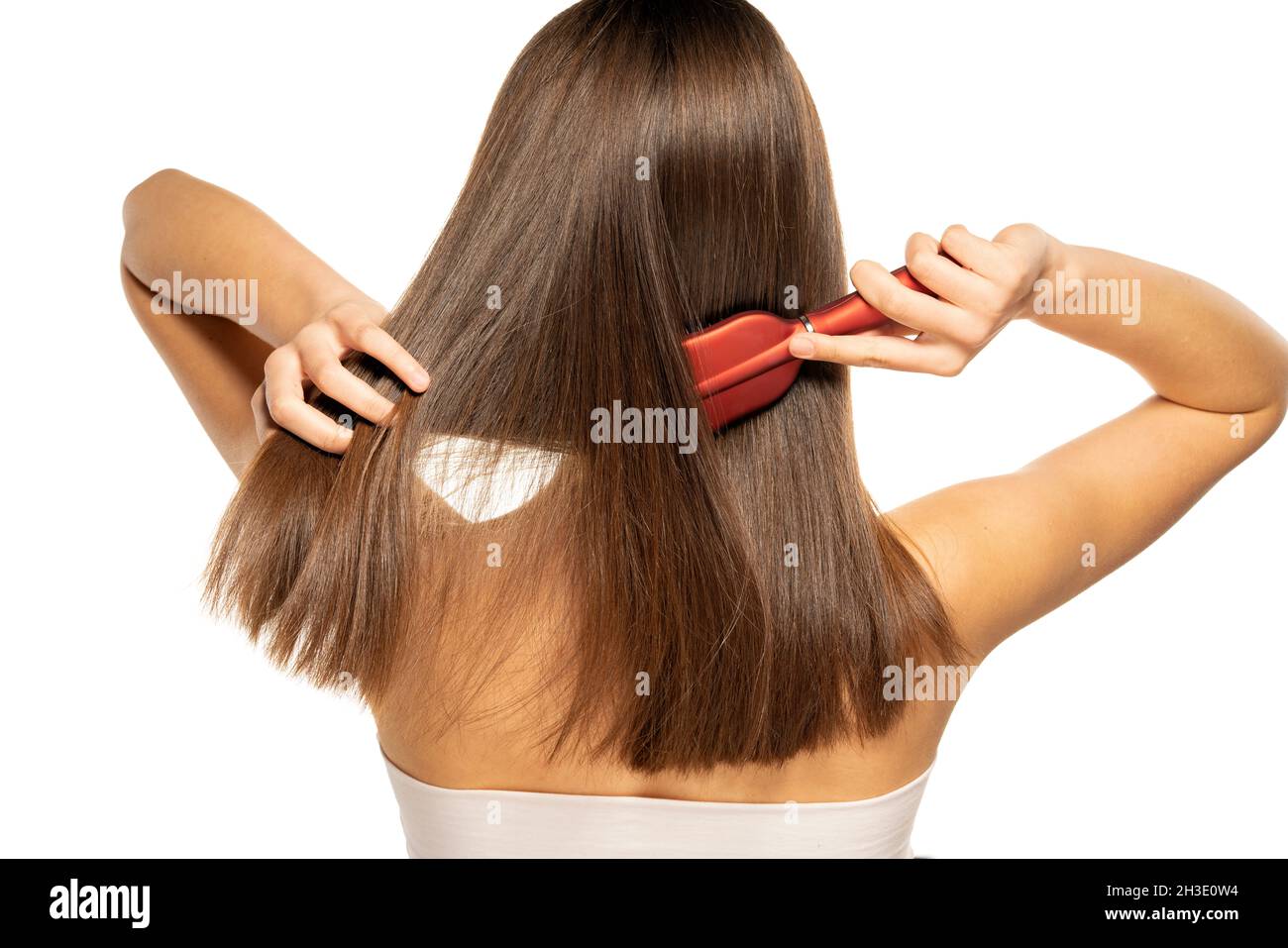 a rear view of a woman brushing her hair against a white background ...
