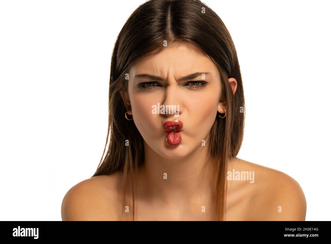 A young funny woman with blue eyes making a fish face on a white ...