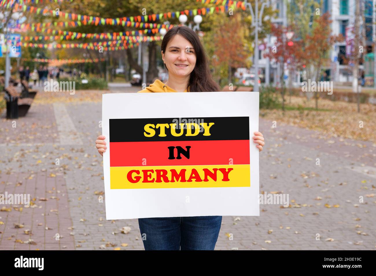 A woman smiles and holds a poster with the text Study in Germany Stock ...