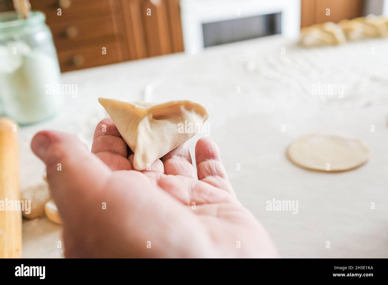 Grandmother holds in her hand a freshly molded manta. A dish of dough ...