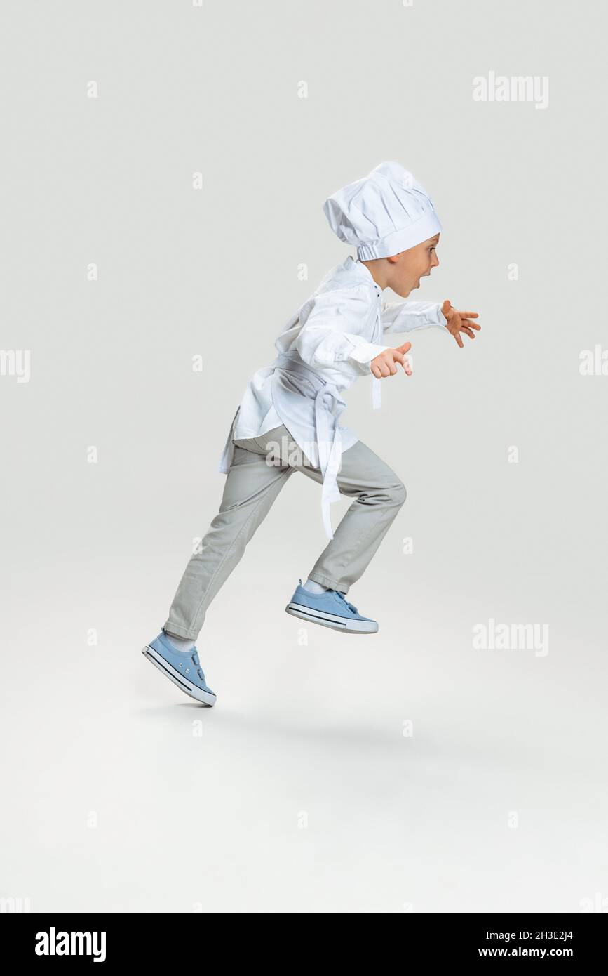 One little preschool boy in white cook uniform and huge chef's hat ...