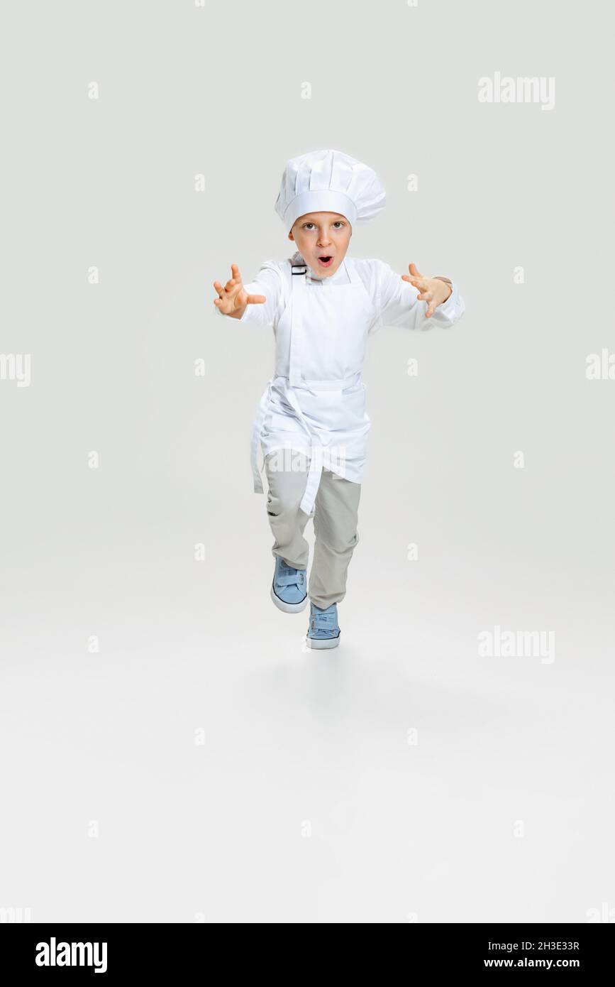 One little preschool boy in white cook uniform and huge chef's hat ...