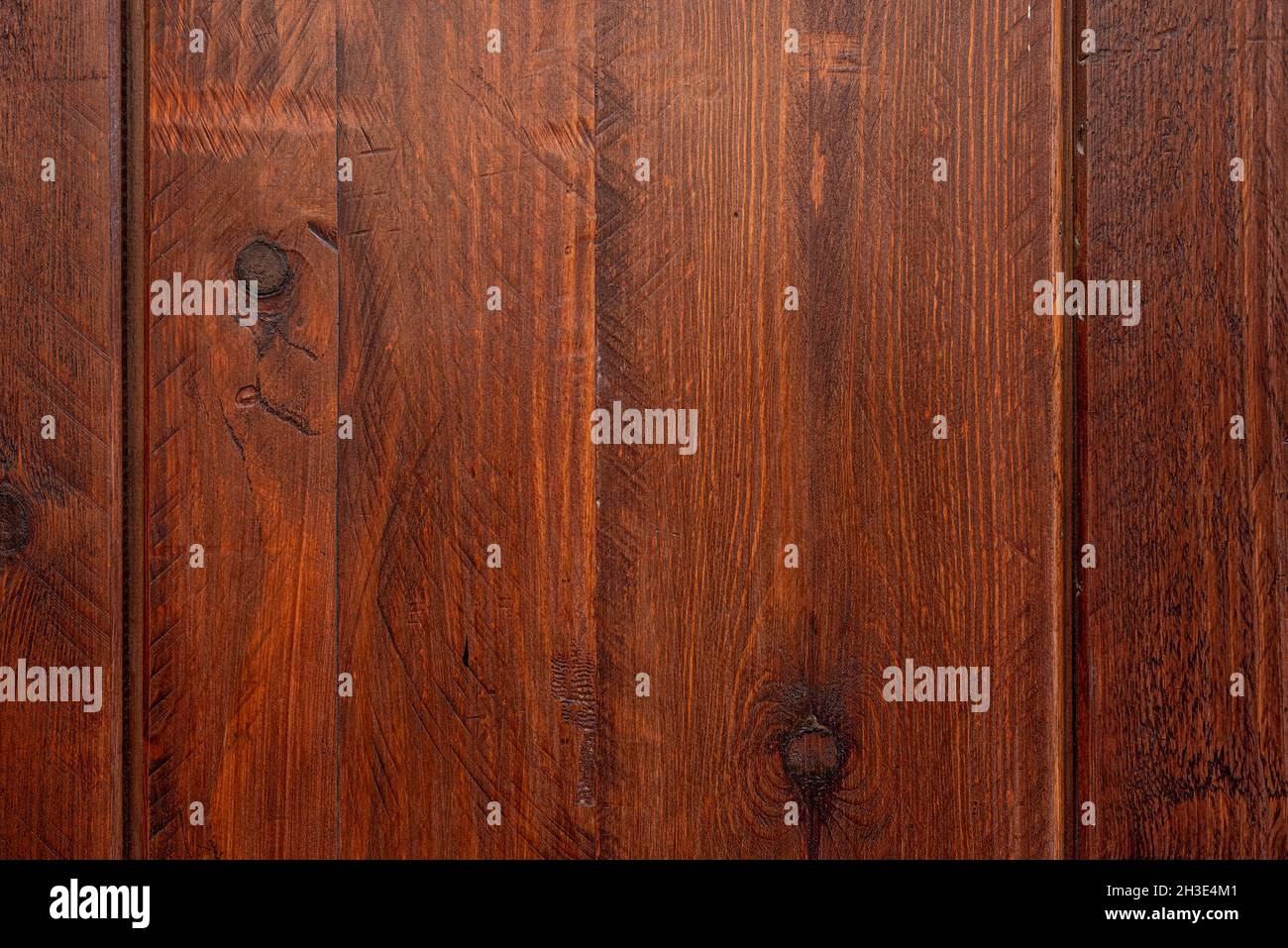 Wooden plank with saw marks and dark knots varnished in a reddish tone ...