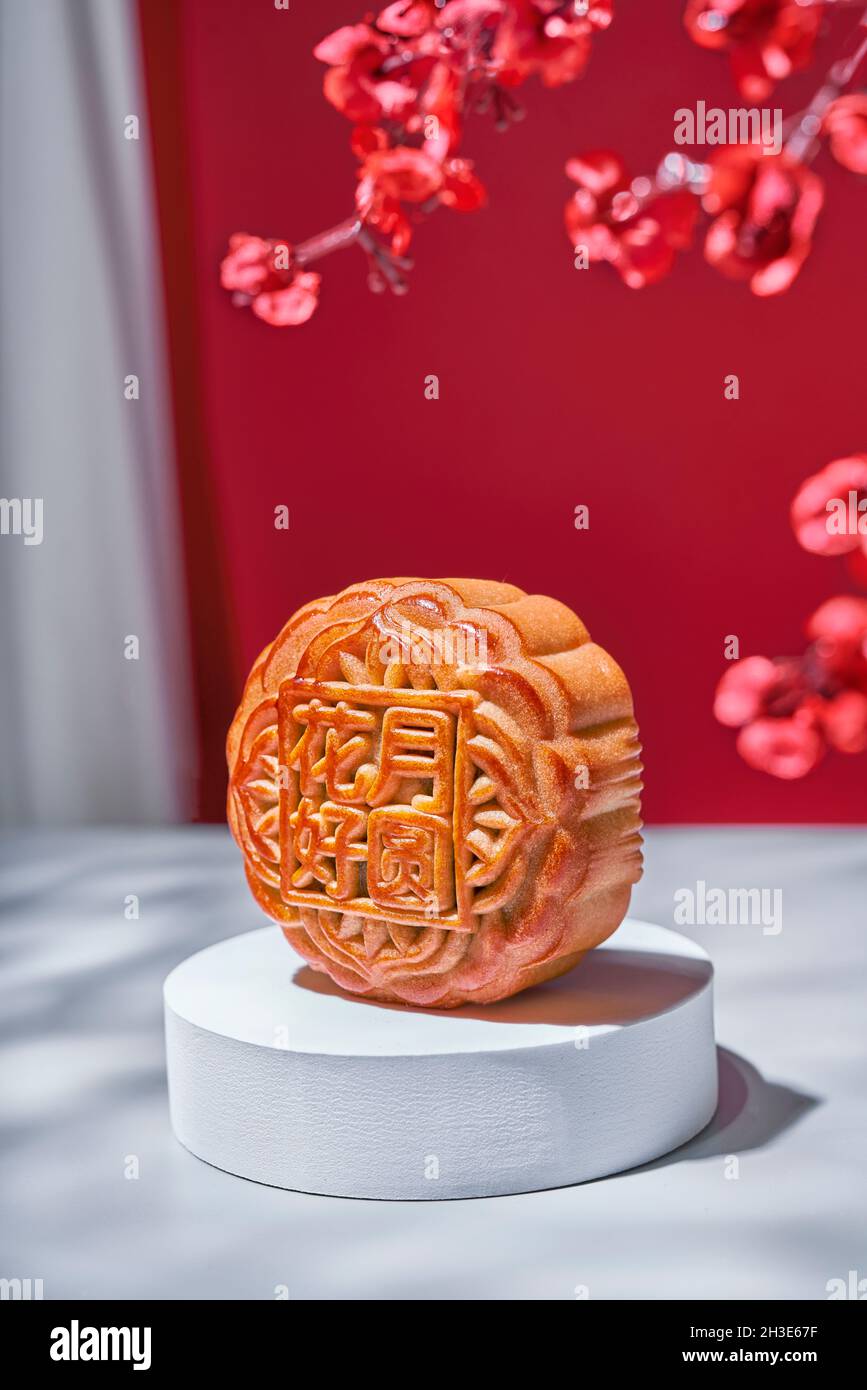 Round Chinese traditional sweet baked mooncake served on stand on table ...