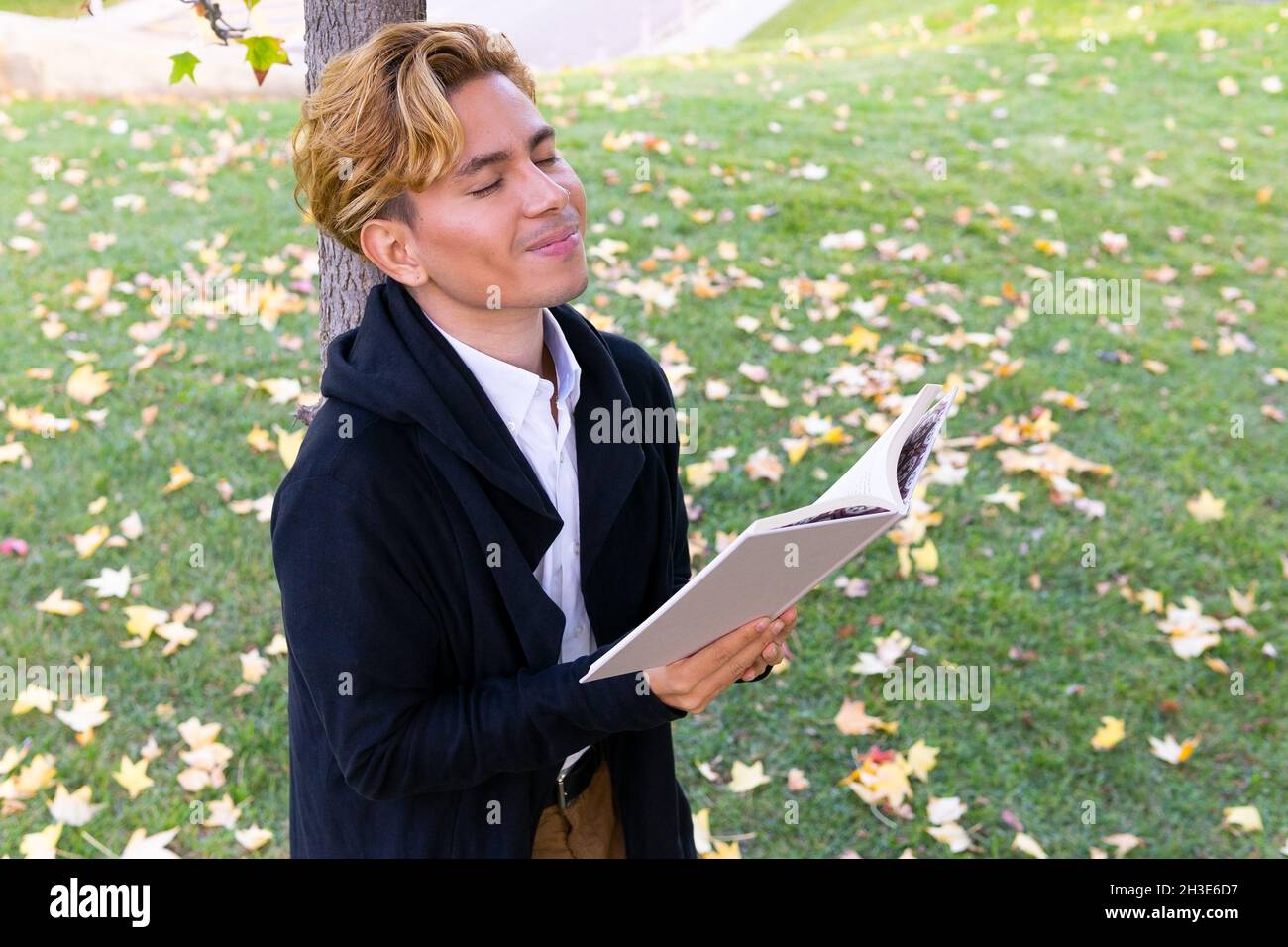 Female student lying on bed and writing in notepad while doing homework ...