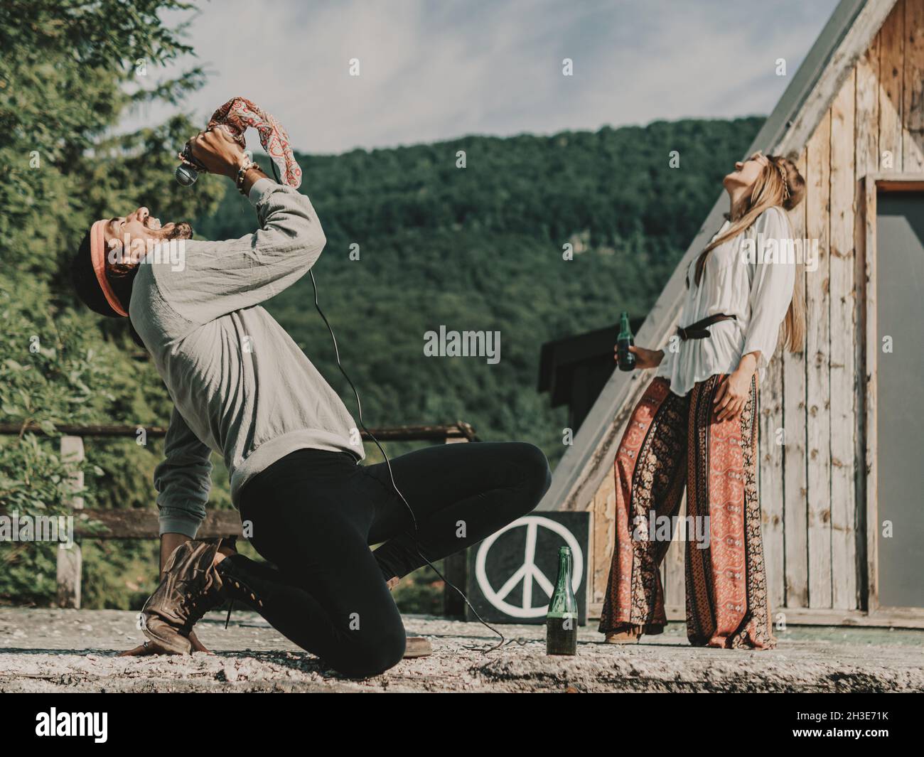 Full body side view of hippie couple singing and drinking alcohol ...