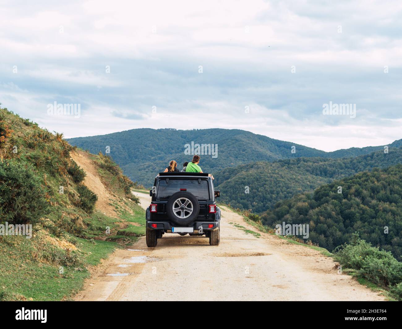 Back view of unrecognizable travelers standing in SUV car driving along ...