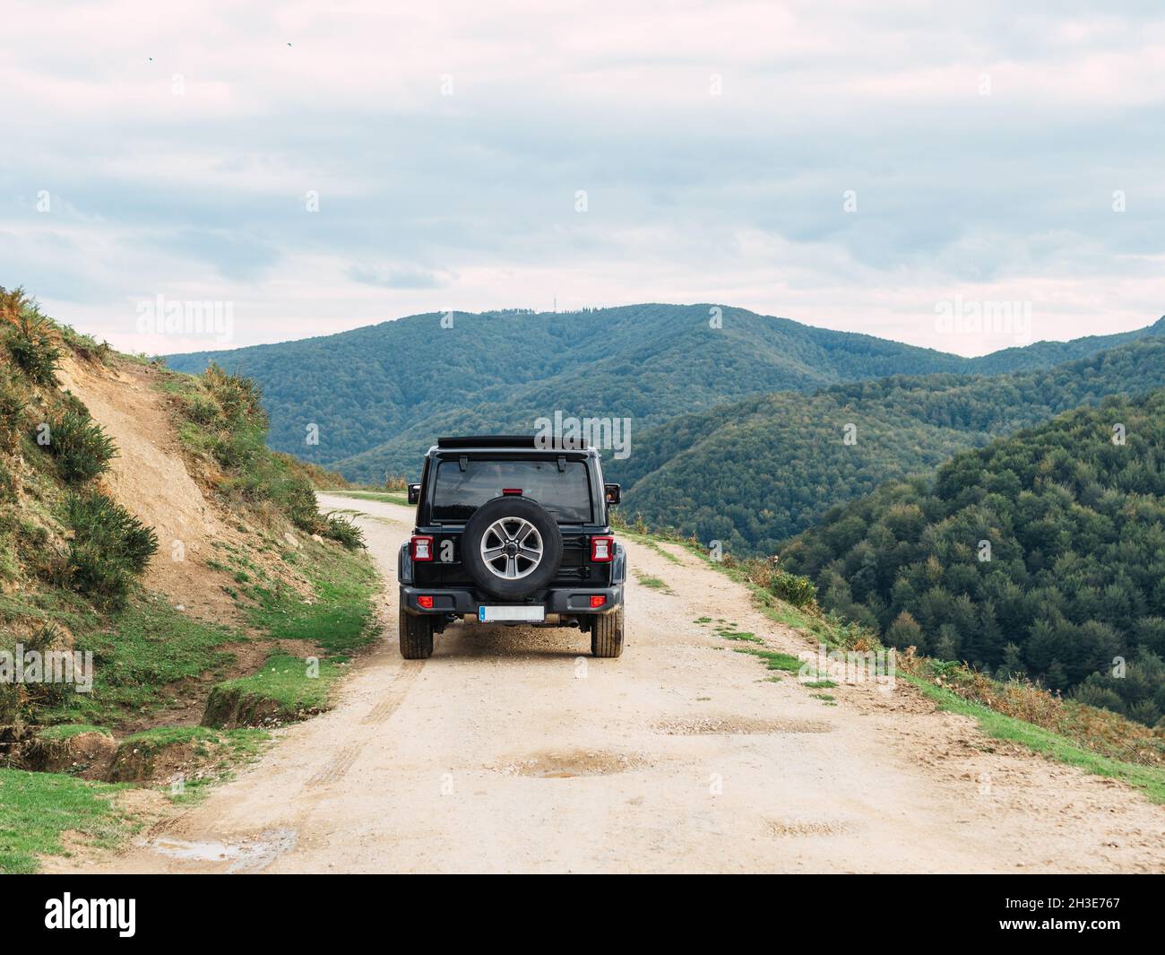 Back view of SUV car driving along rough road during trip in ...