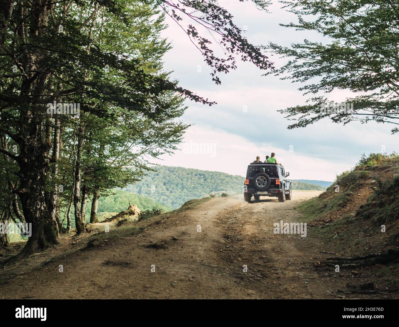 Back view of unrecognizable travelers standing in SUV car driving along ...