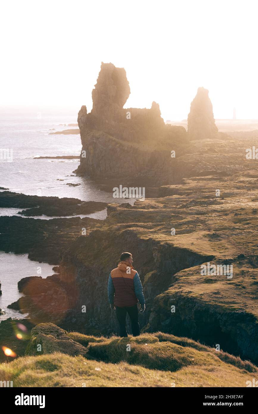 Back view of anonymous male hike in warm outerwear standing on rocky ...