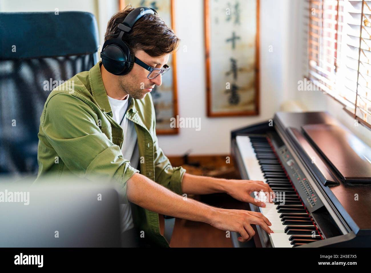Side view of male musician in casual clothes playing melody on piano ...