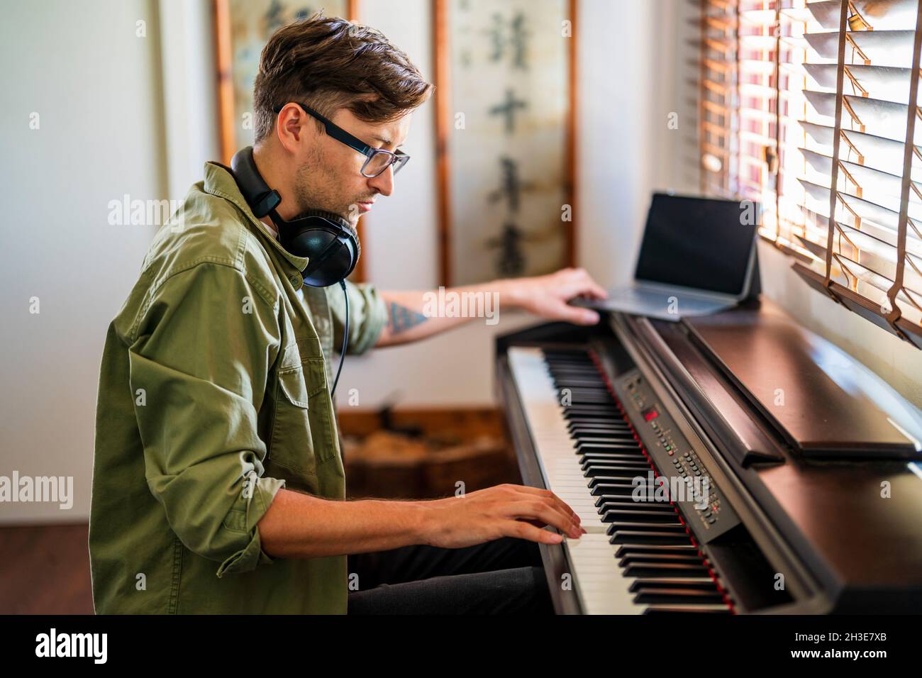 Side view of male musician in casual clothes playing melody on piano ...