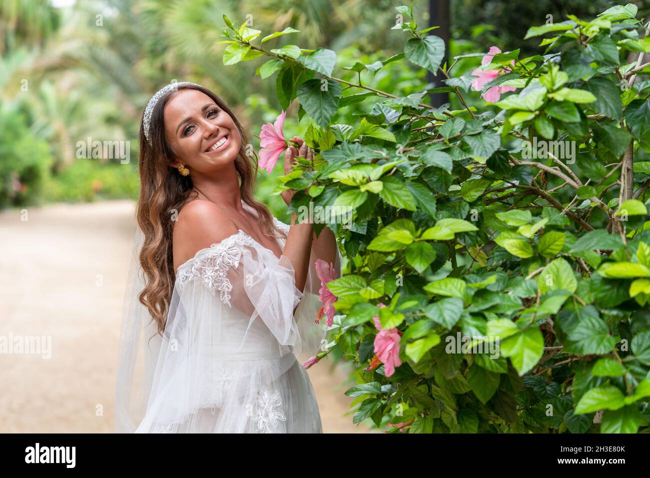 Cheerful bride in wedding dress looking at camera with smile while ...