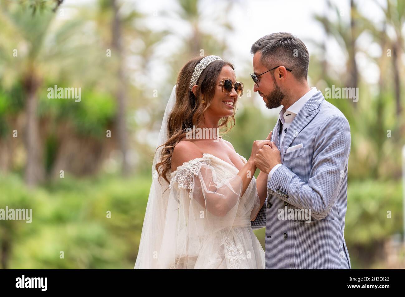 Side view of happy young married couple in wedding clothes standing and ...