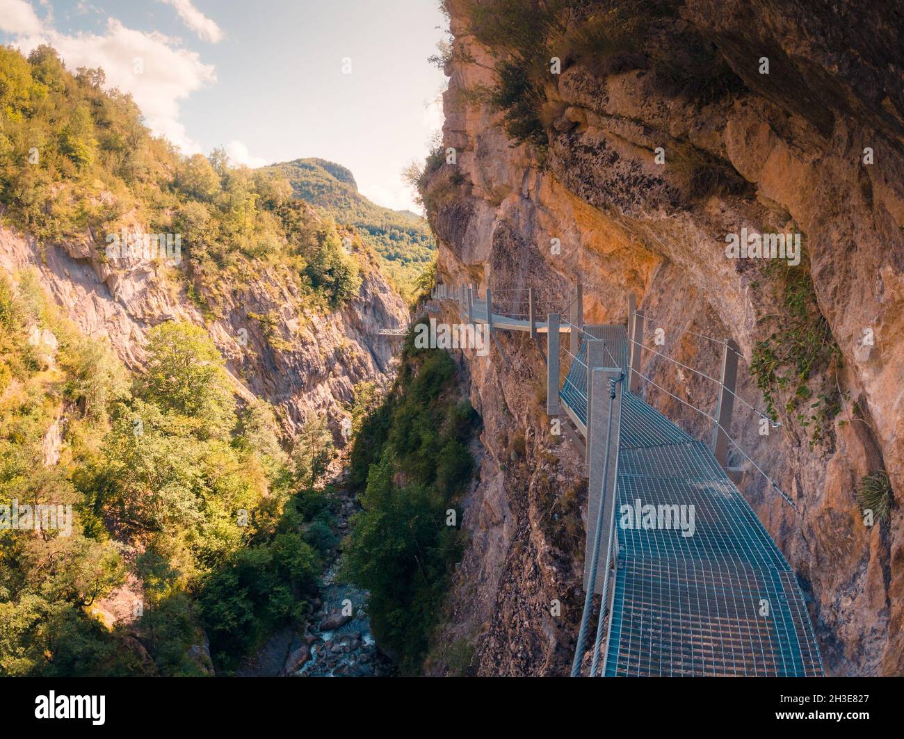 Long suspension footbridge with railing hanging among rough rocky ...