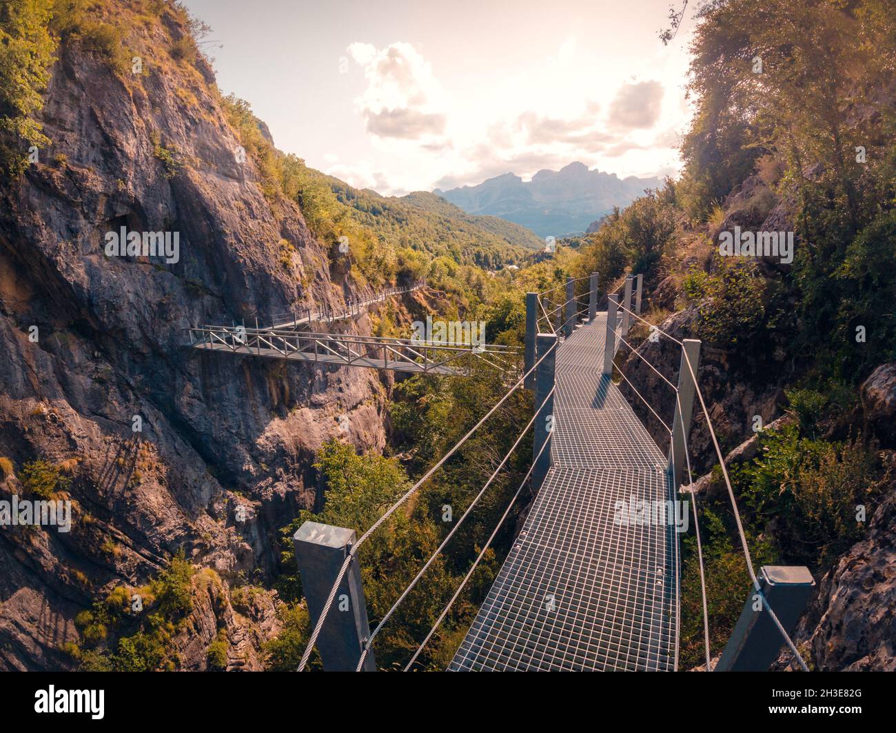 Long suspension footbridge with railing hanging among rough rocky ...