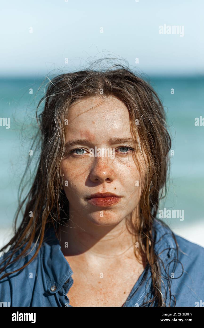 Female in wet shirt and with wet hair standing looking at camera on ...
