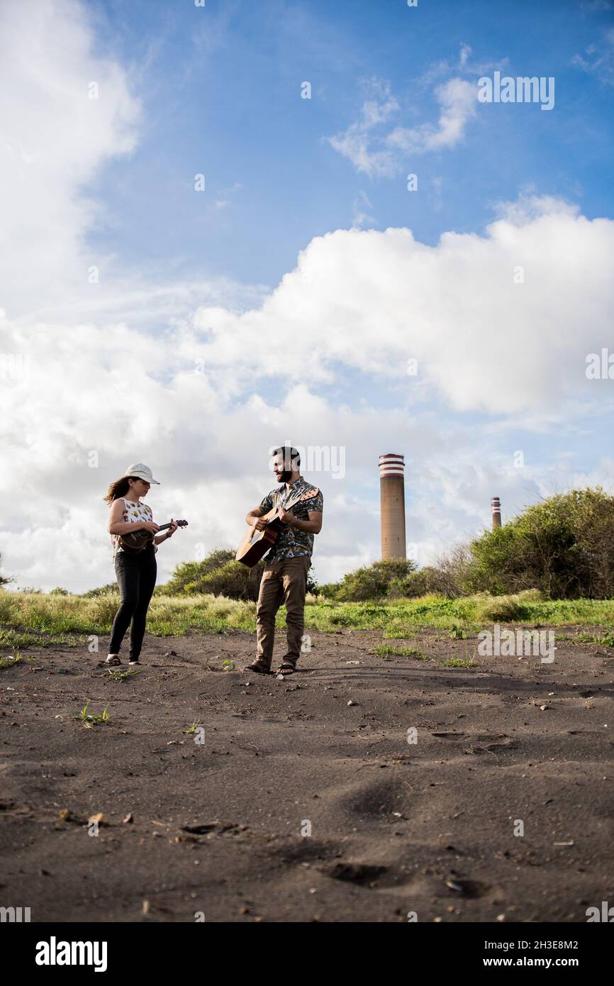 Full body of male musician playing acoustic guitar and looking at ...