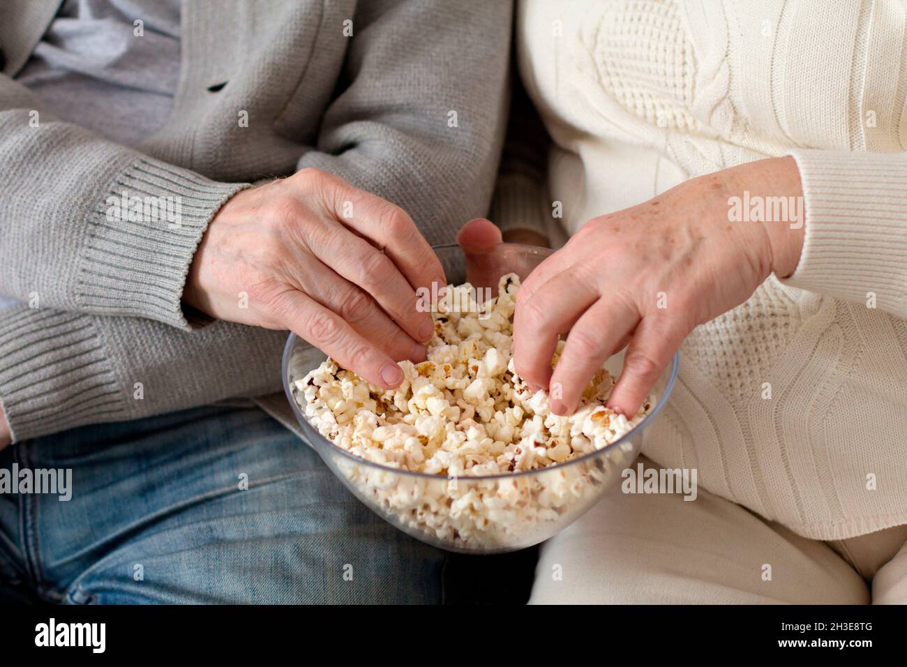 Two aged people eating popcorn together. Hands of elderly people ...