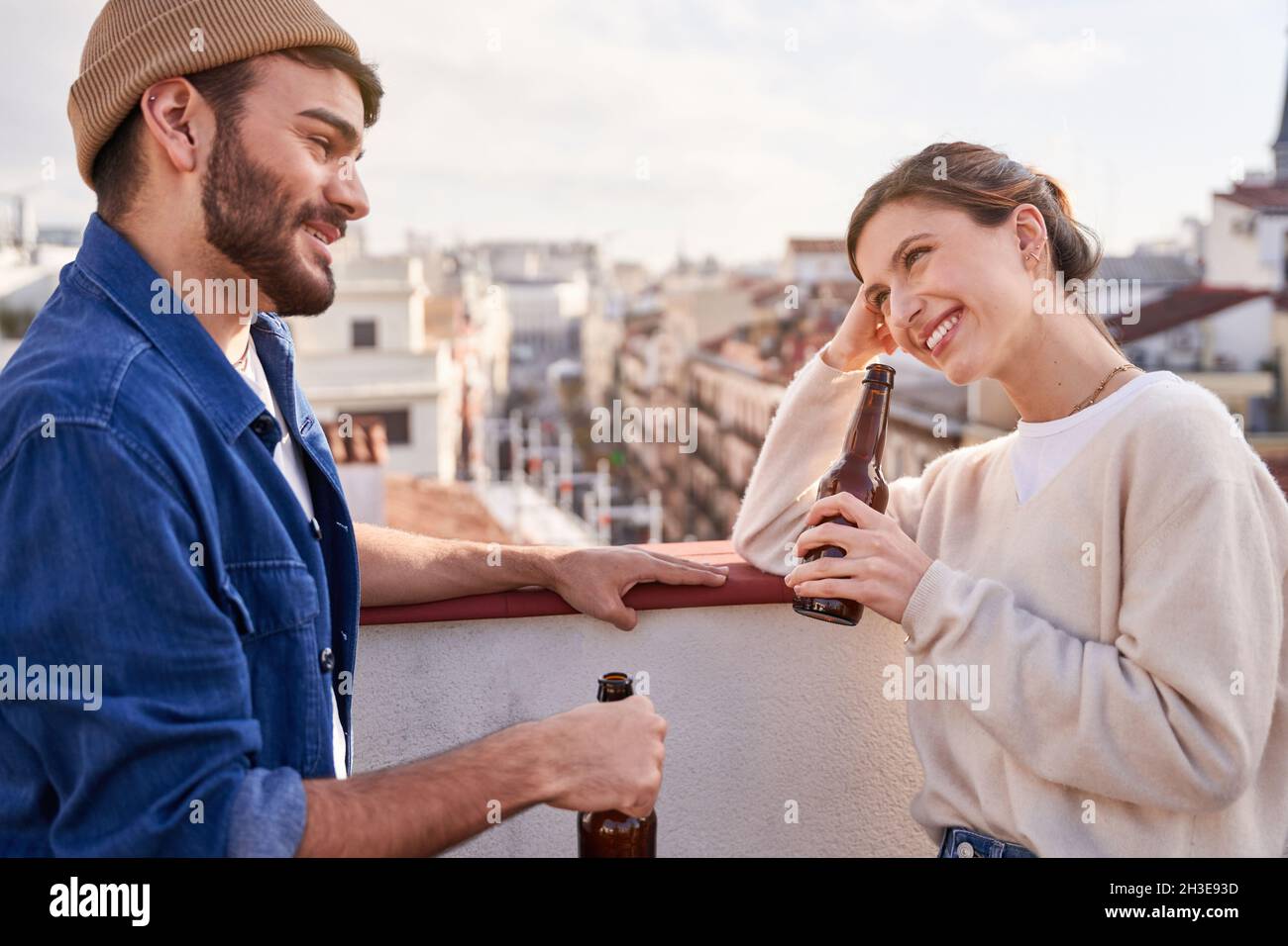 Full body of cheerful friends raising bottles of beer while laughing on ...