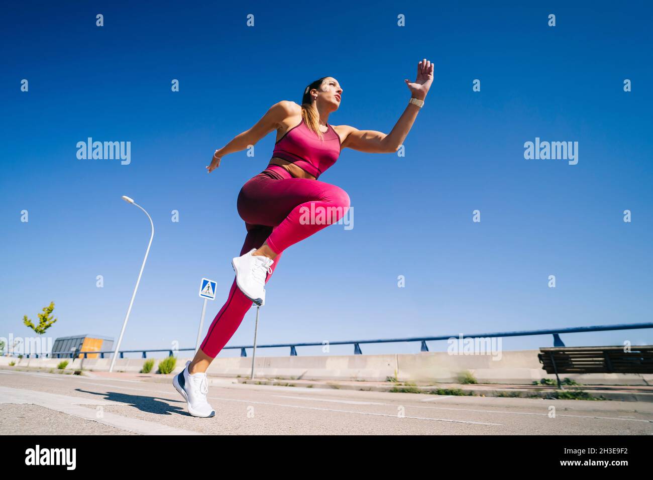 Low angle of female running fast on asphalt road during workout under ...