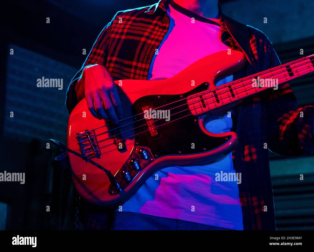 Crop anonymous male guitarist playing electric guitar in club with neon ...
