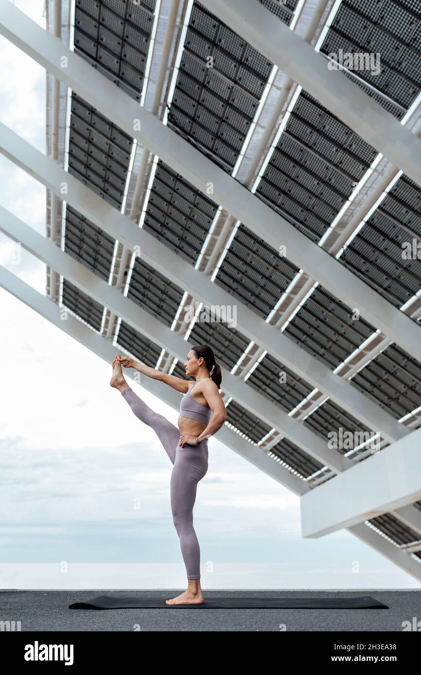 Full body side view of active female balancing while practicing Utthita ...