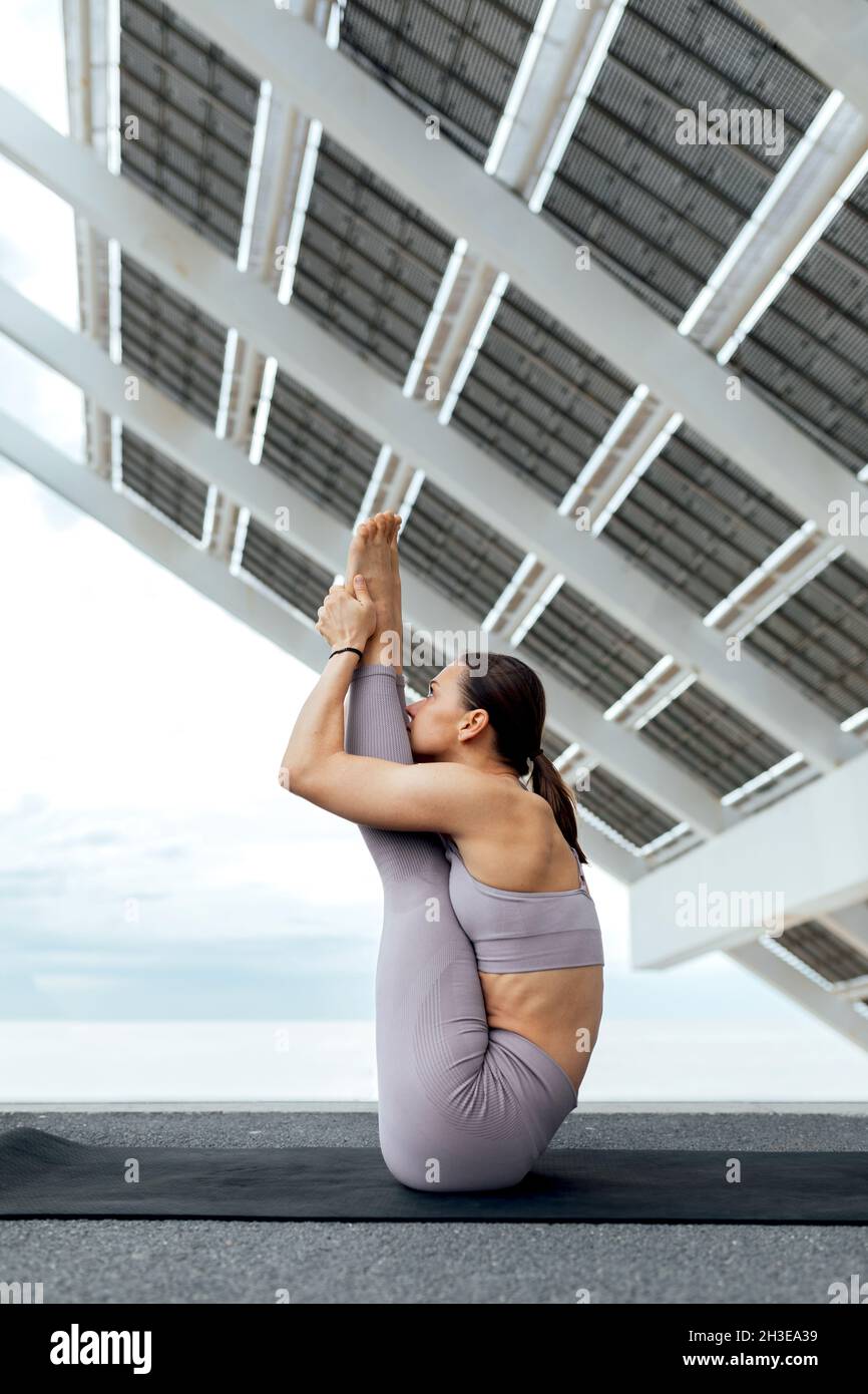 Full body side view of sportive female practicing Urdhva Mukha ...