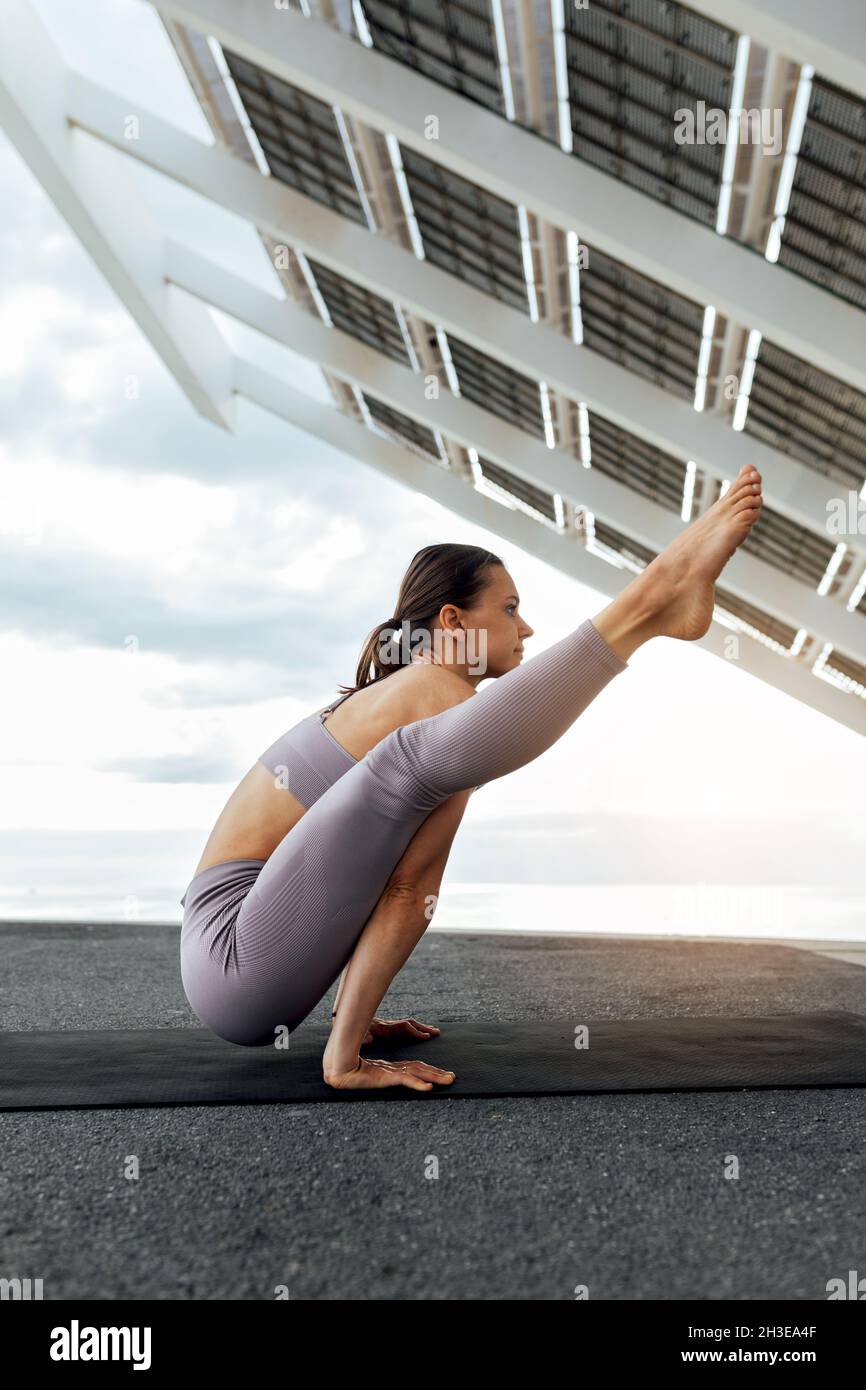 Full body side view of strong sportsWoman doing Tittibhasana posture on ...