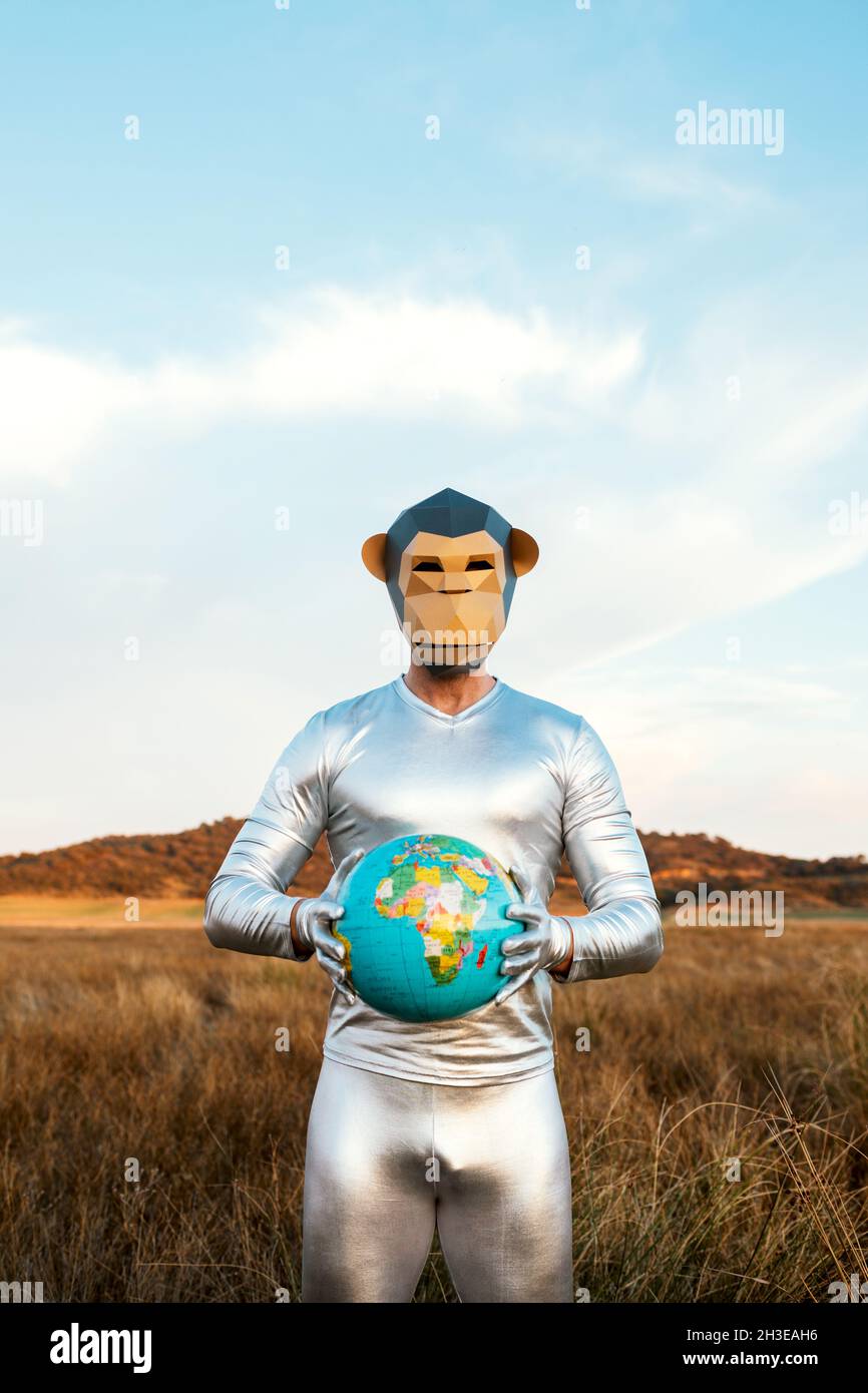 Anonymous guy in silver latex suit with geometric monkey mask looking ...