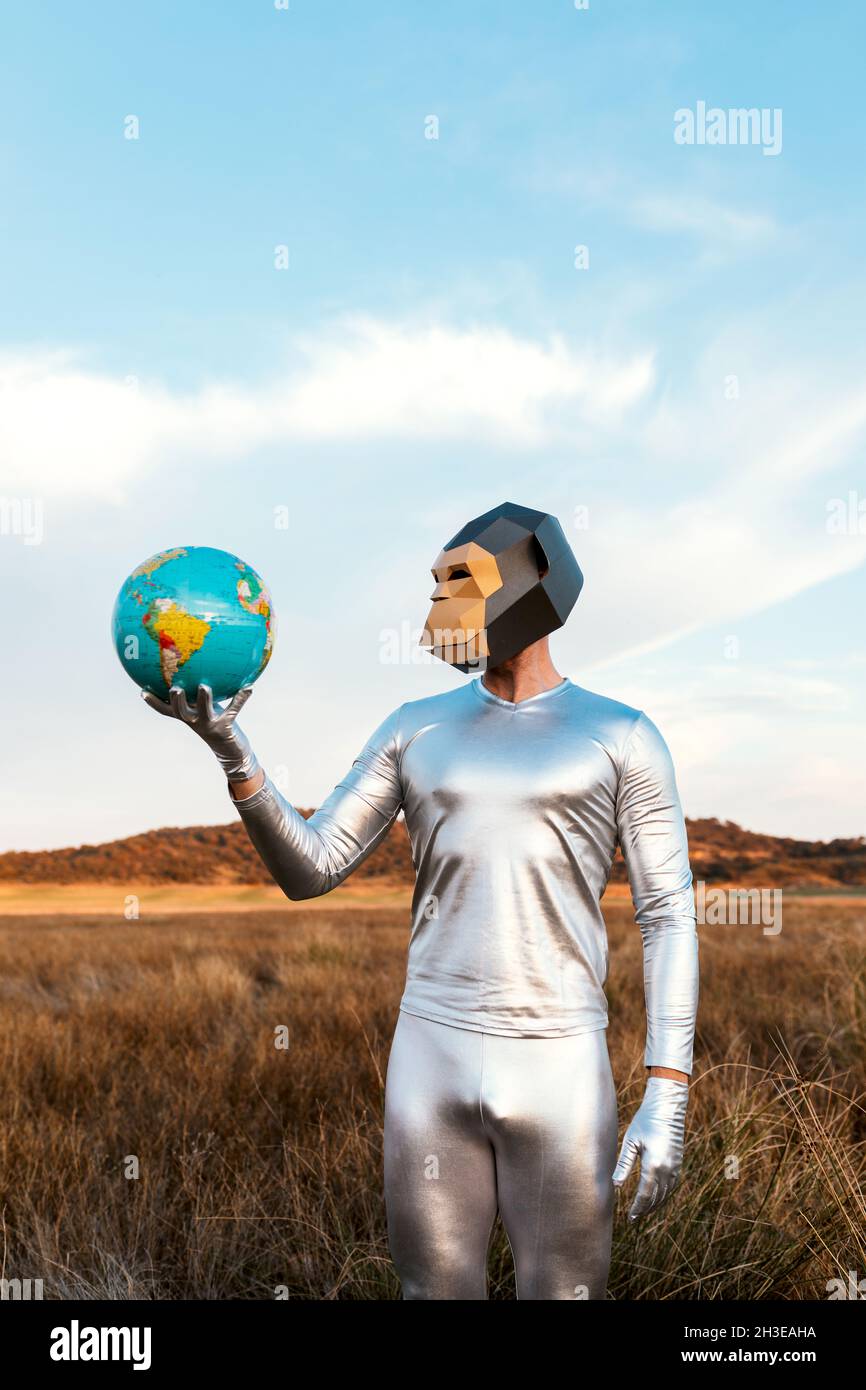 Anonymous guy in silver latex suit with geometric monkey mask looking ...