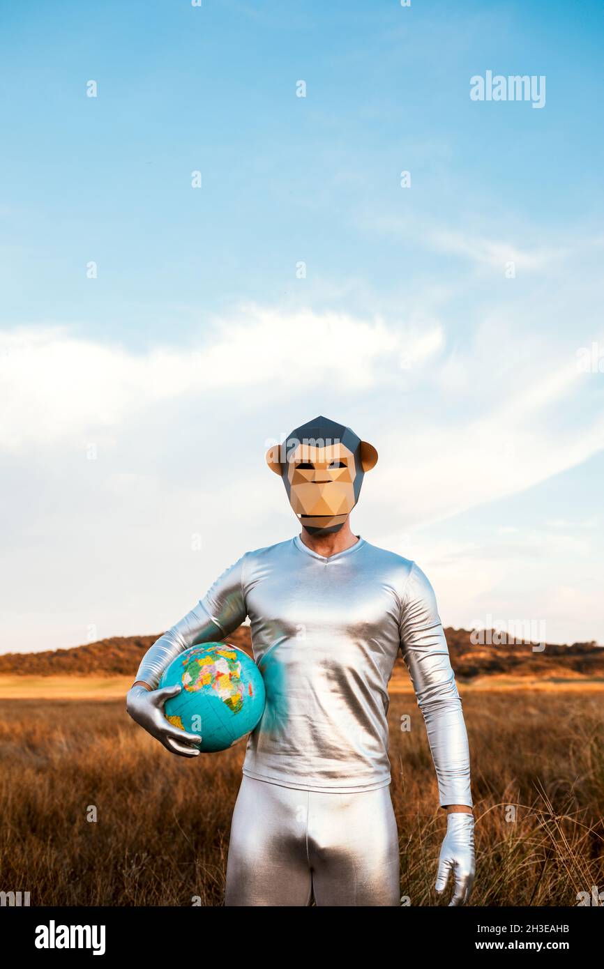 Anonymous guy in silver latex suit with geometric monkey mask looking ...