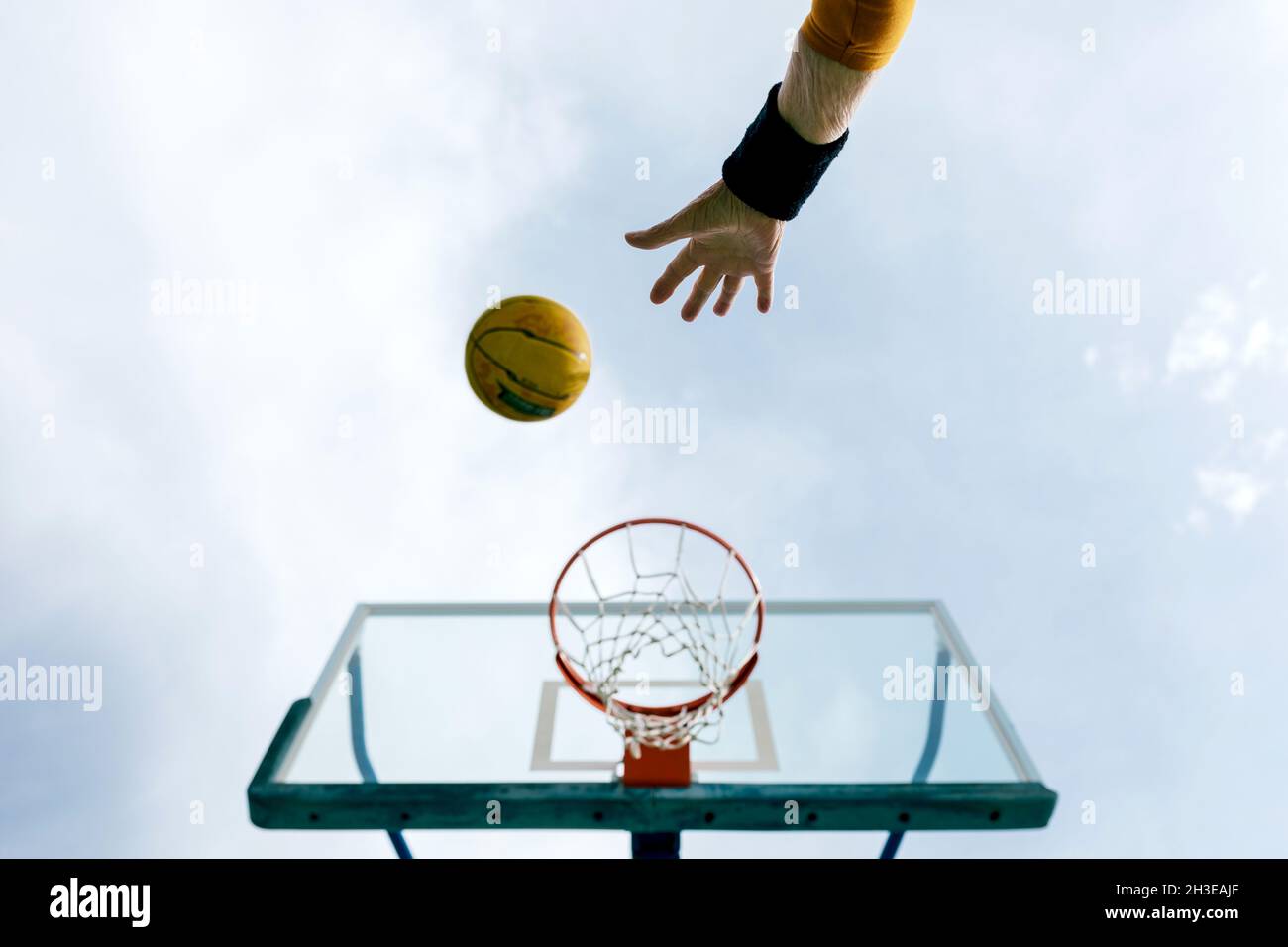 From below of crop anonymous person throwing basketball ball into hoop ...