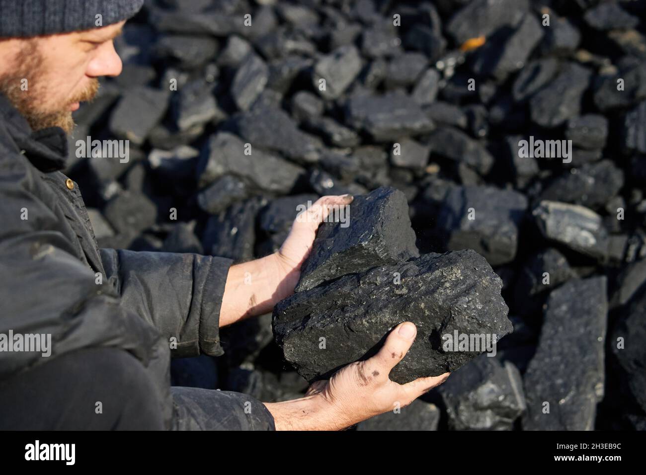 poor middle-aged man holding the hands of stone coal for sale to ...