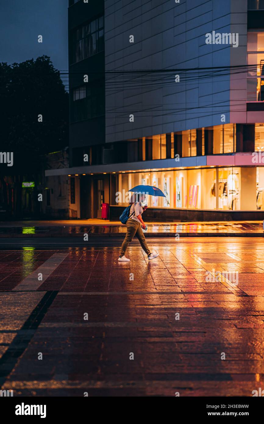 Girl walking in a city, on a rainy night with umbrella and city lights Stock Photo - Alamy