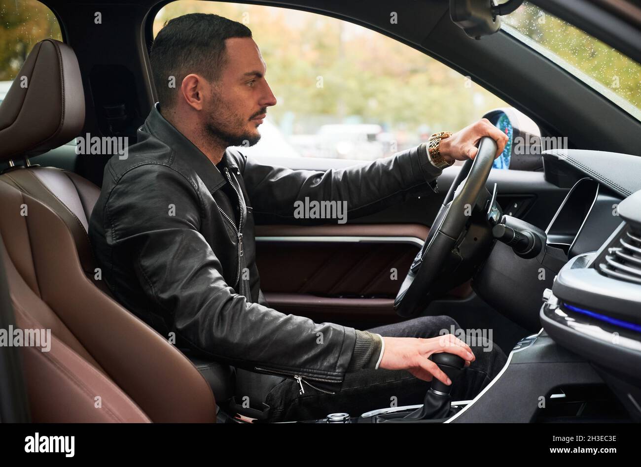 Side view inside car. Attractive boy driving his comfortable modern ...