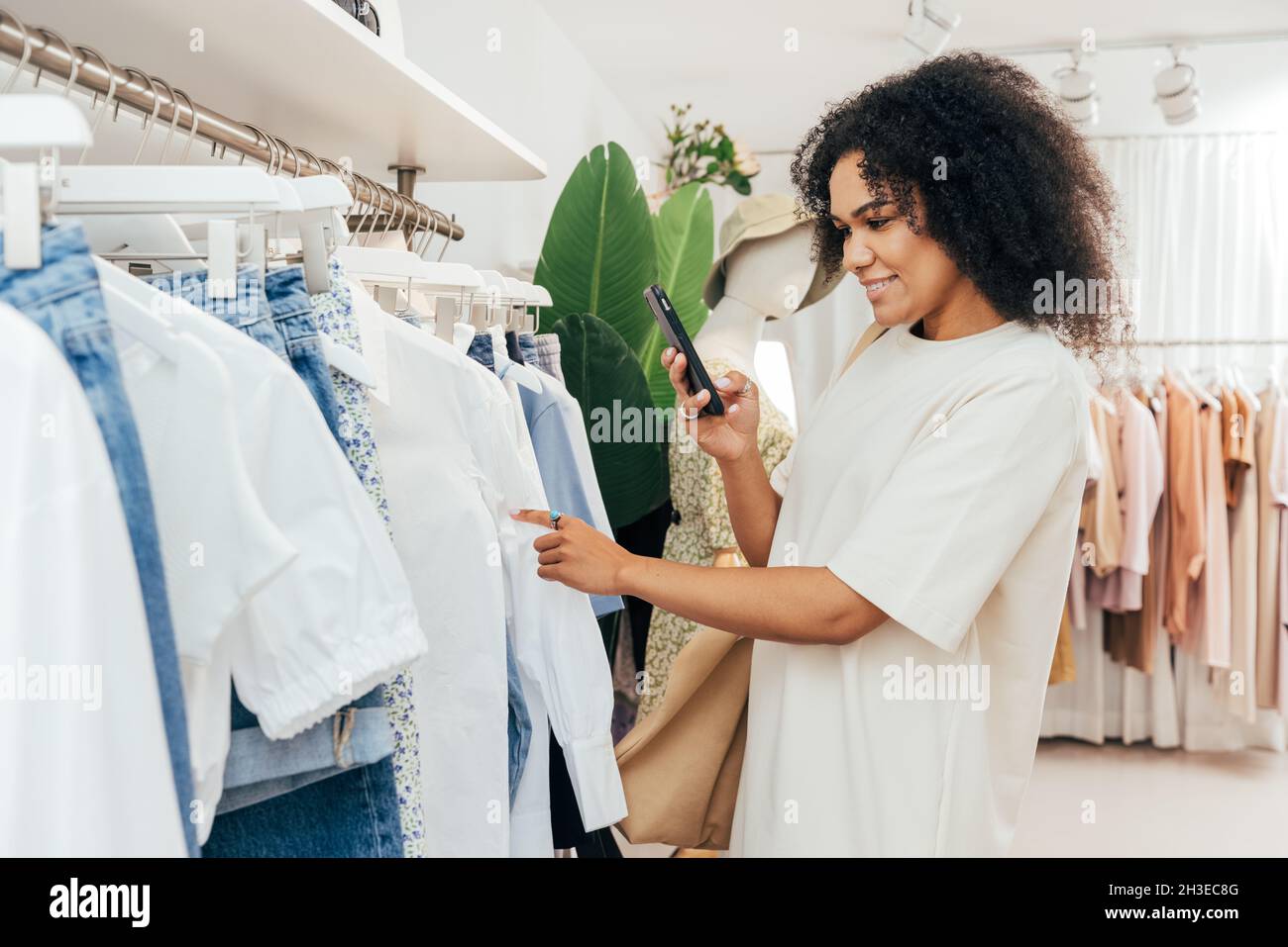 Side view of young woman photographing clothes in shop Stock Photo - Alamy