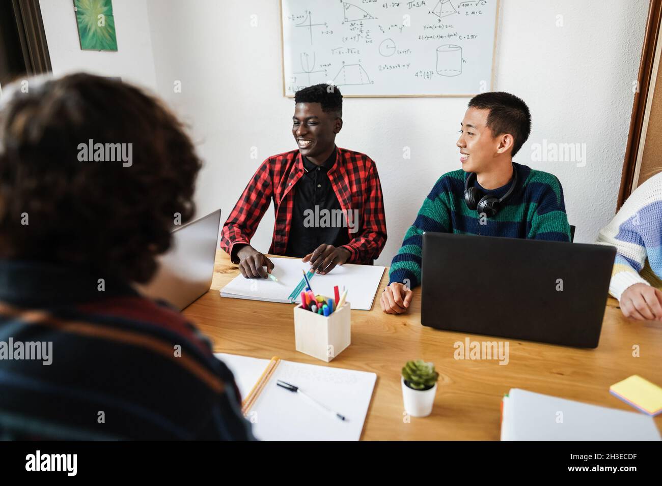 Multiracial students using laptop computers while studying together at ...