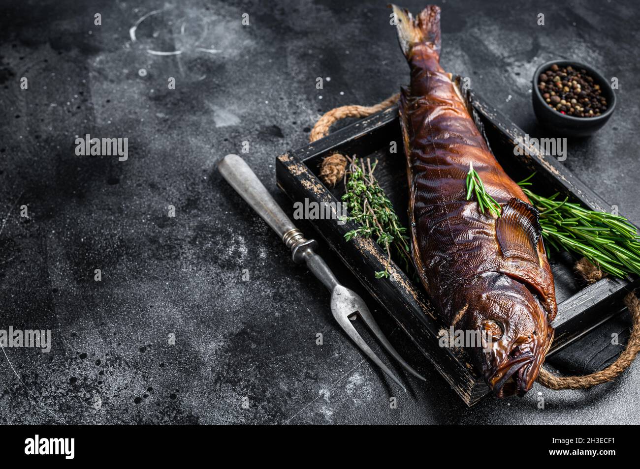 Hot smoked pike perch or zander fish in a wooden tray. Black background ...