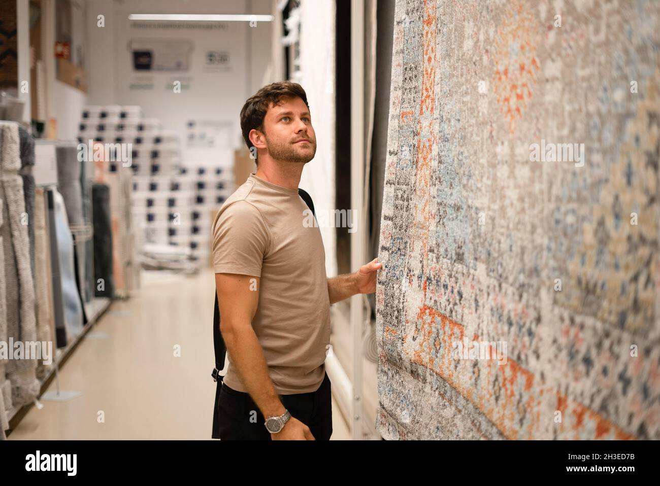 Handsome casual guy looking at rack and exploring textile of hanging ...