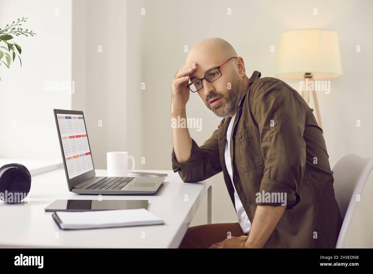 Busy man overwhelmed with work using calendar on laptop and planning ...