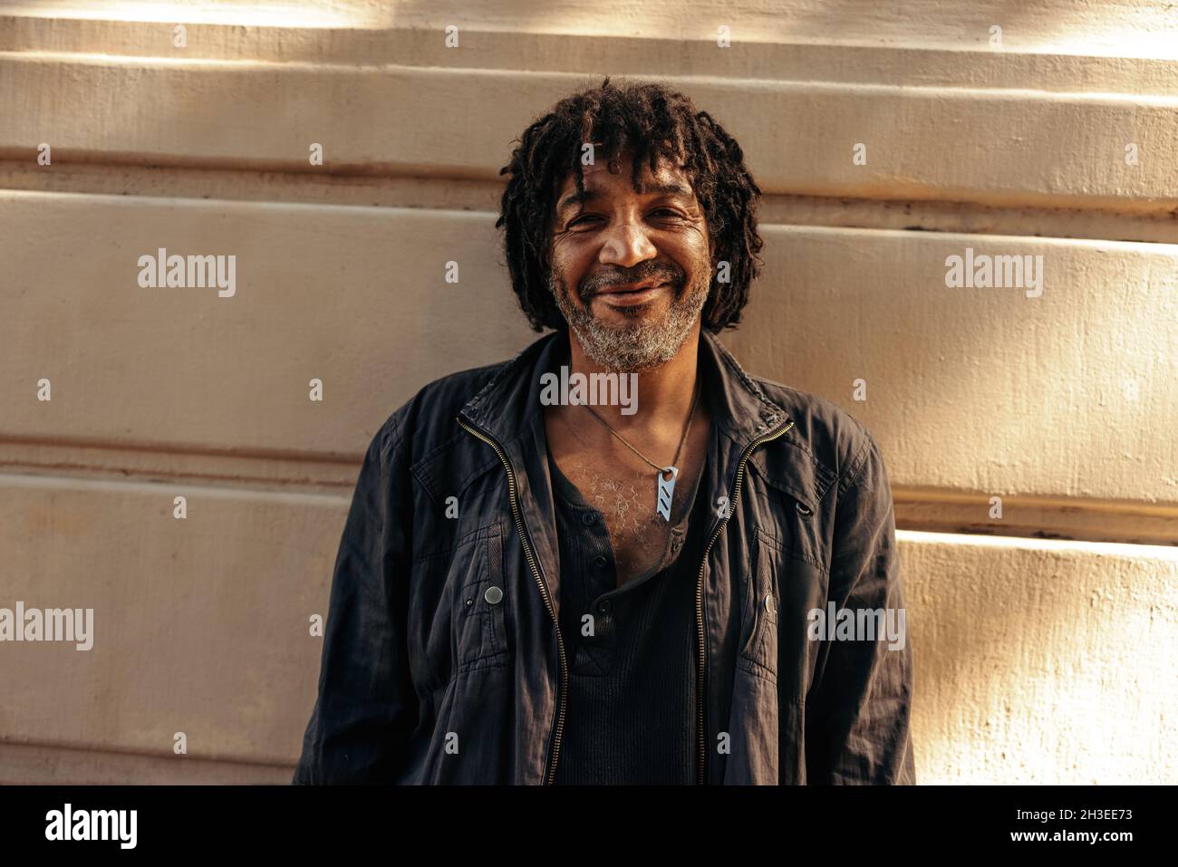 Happy homeless man smiling at the camera cheerfully while standing ...