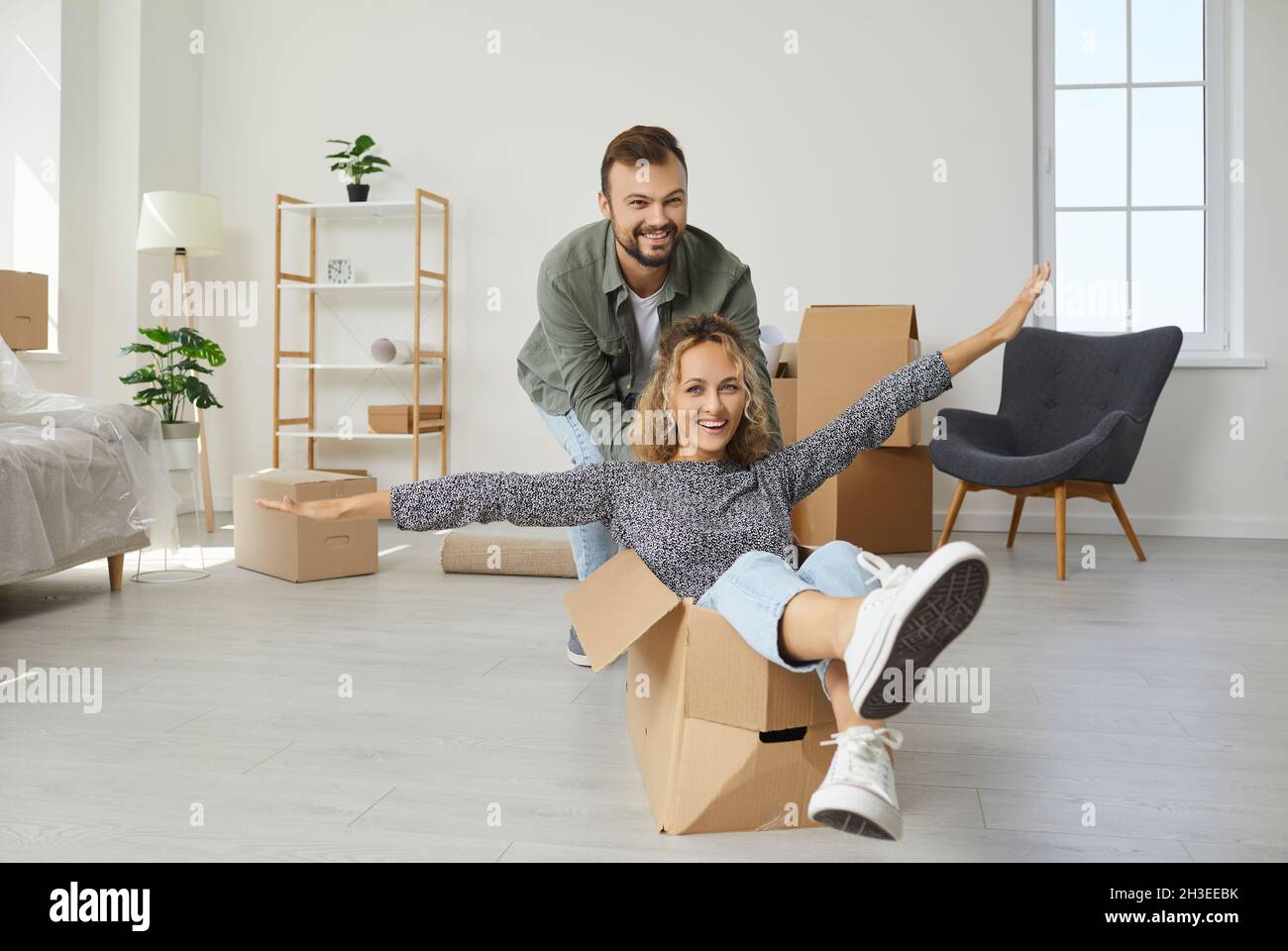 Happy husband and wife having fun in the living room of their new house ...