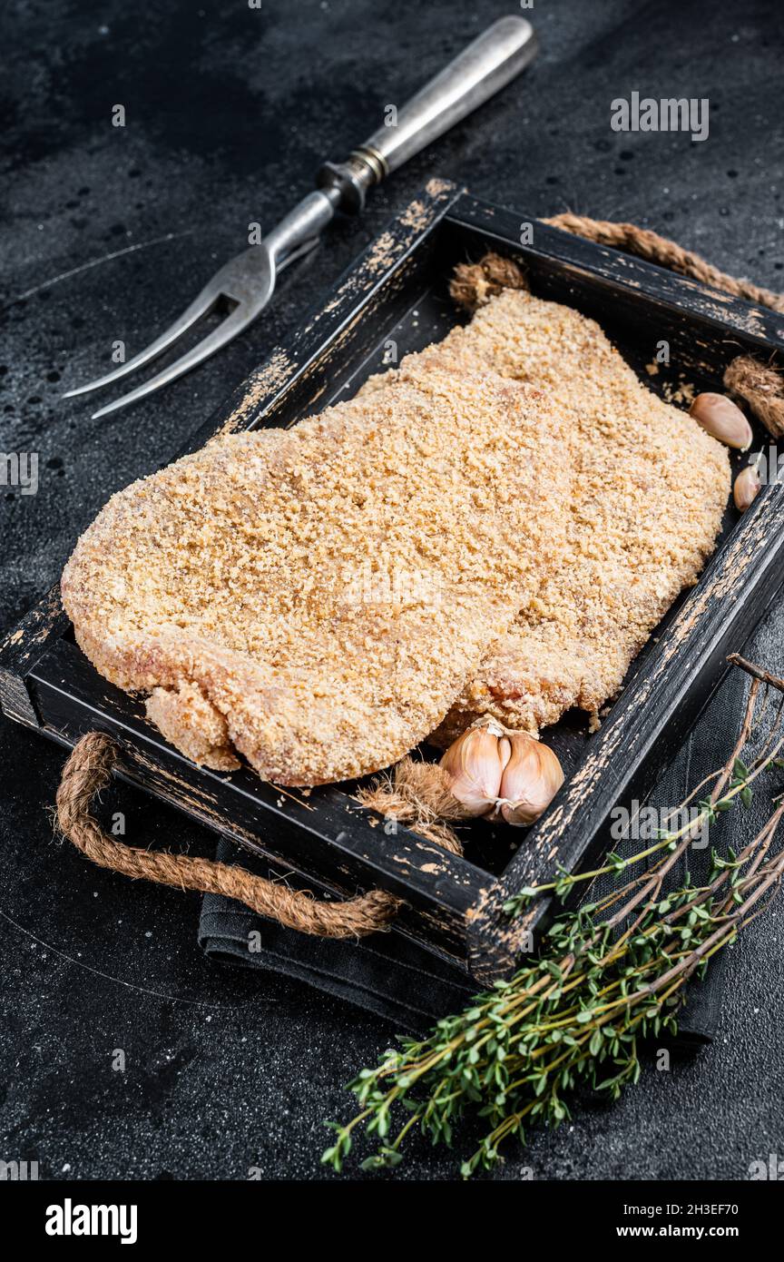 Homemade German Wiener Raw schnitzel in a wooden tray. Black background ...