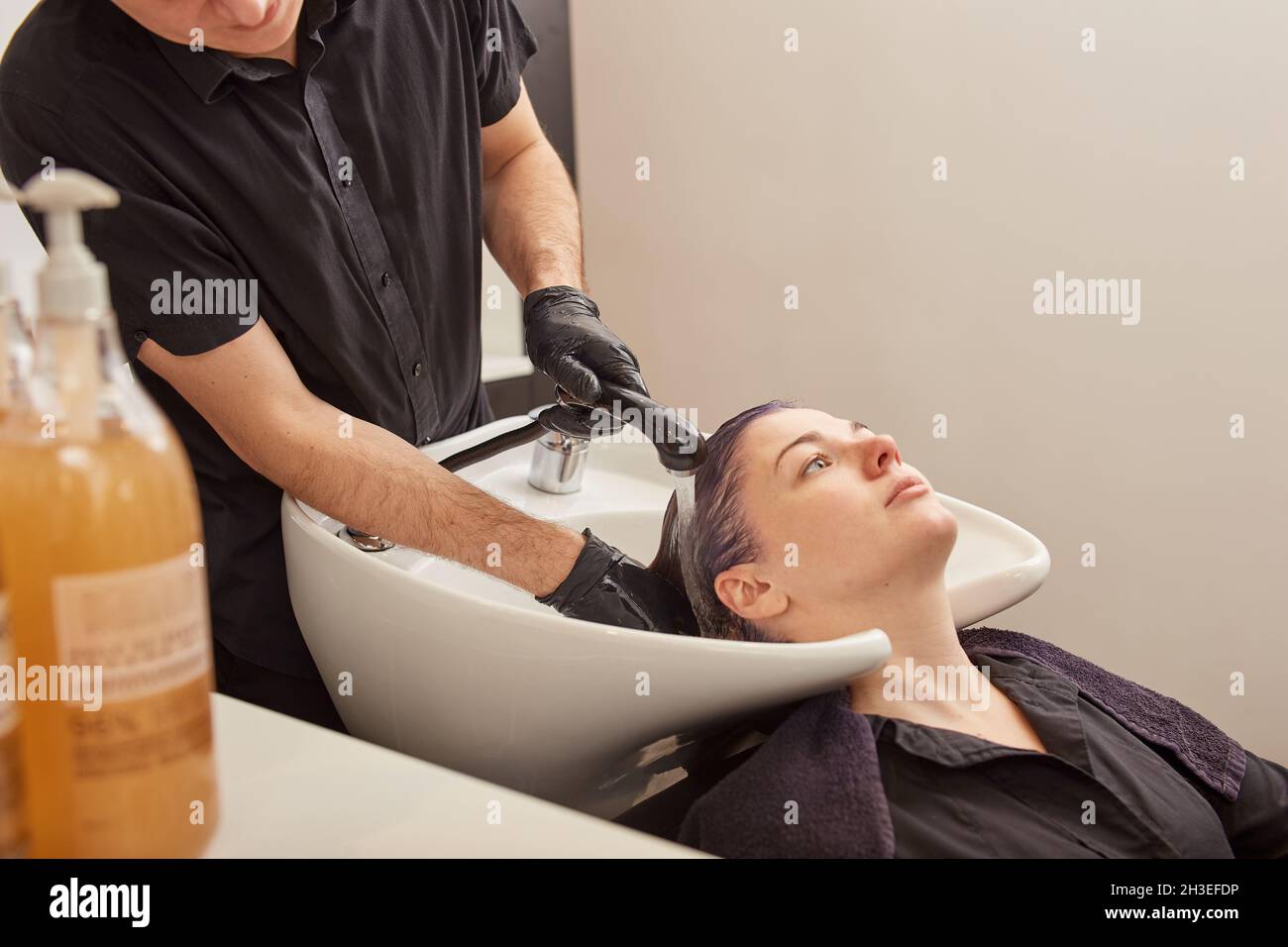 Male hairdresser washing toning shampoo out of client hair Stock Photo ...