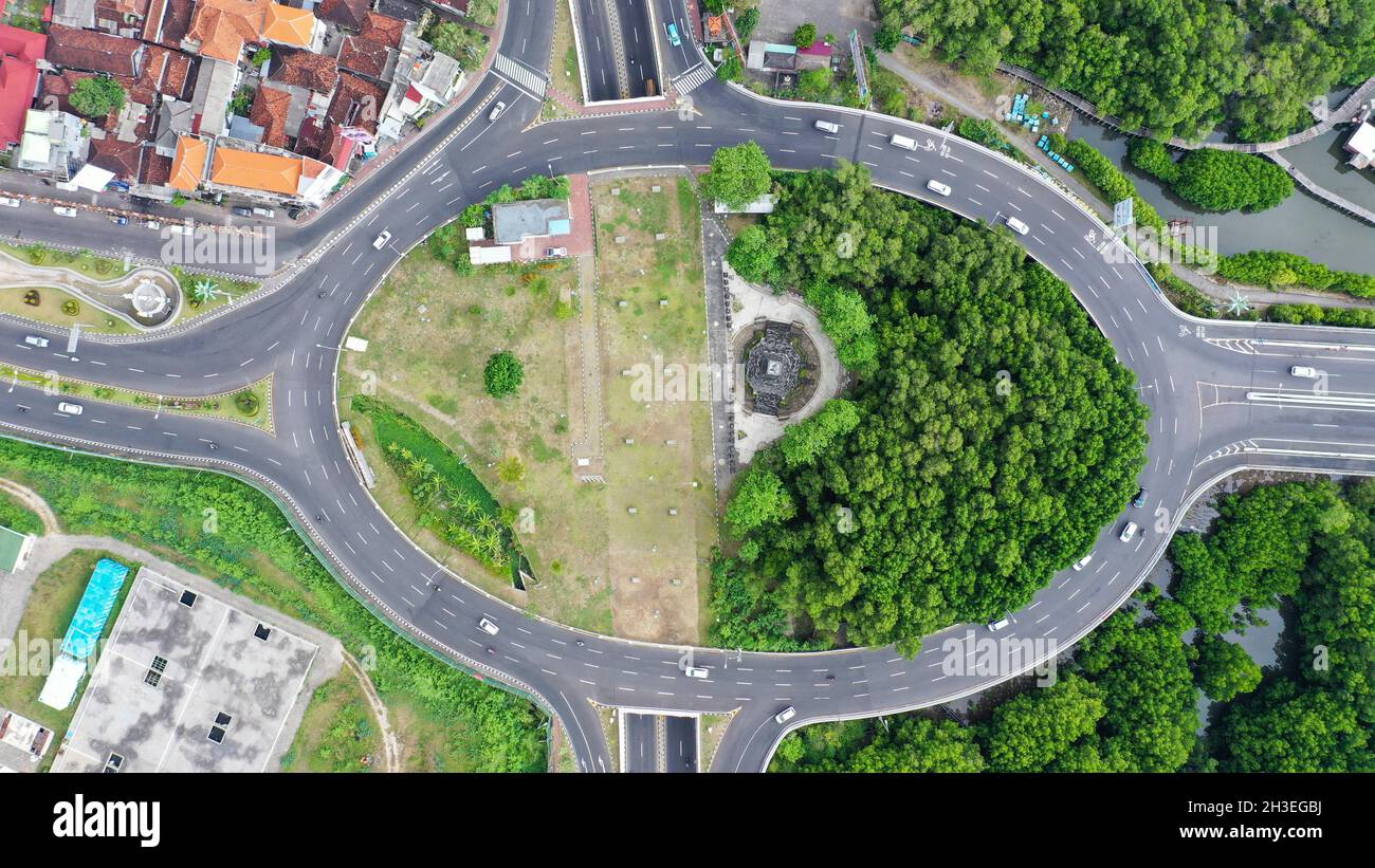 Aerial view of the ring road in Bali with green trees on the middle ...