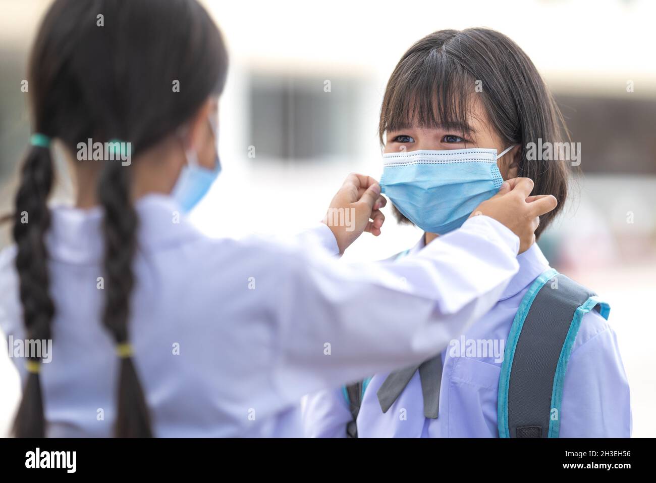 Girl helping her friend wearing a medical mask Stock Photo - Alamy