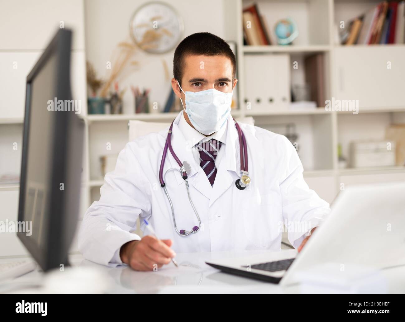 Male therapist in surgical mask holding consultation in office Stock ...